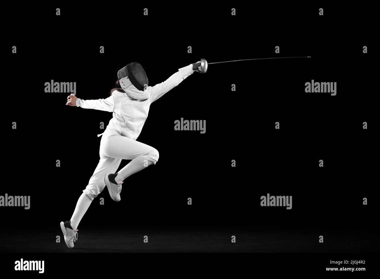 Energetic female fencer in white fencing costume and mask in action ...