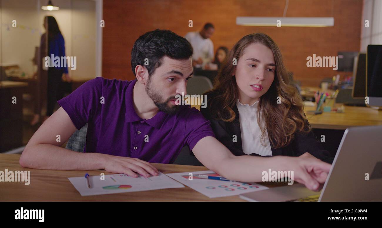 Happy workers looking at laptop screen together. Male pointing at ...