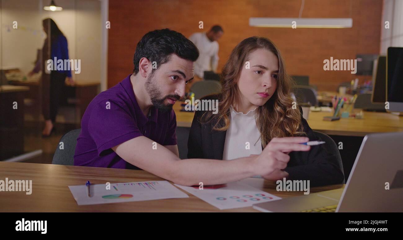 Young office employees at workplace going over results and plan. Male ...