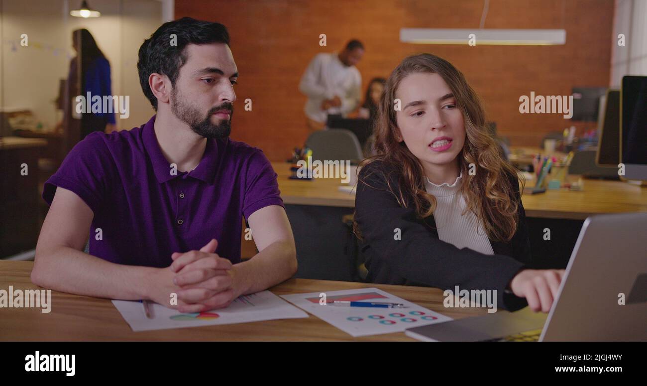 Happy workers looking at laptop screen together. Male pointing at ...