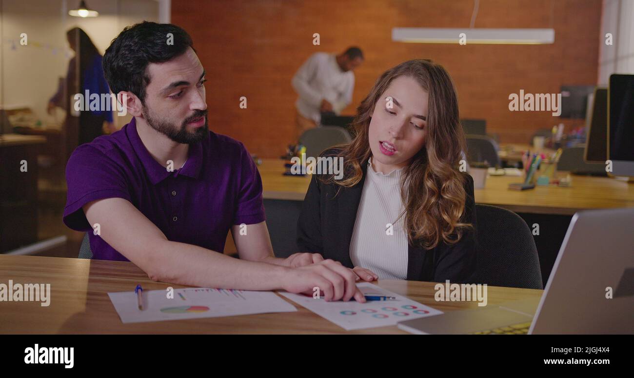Young office employees at workplace going over results and plan. Male ...
