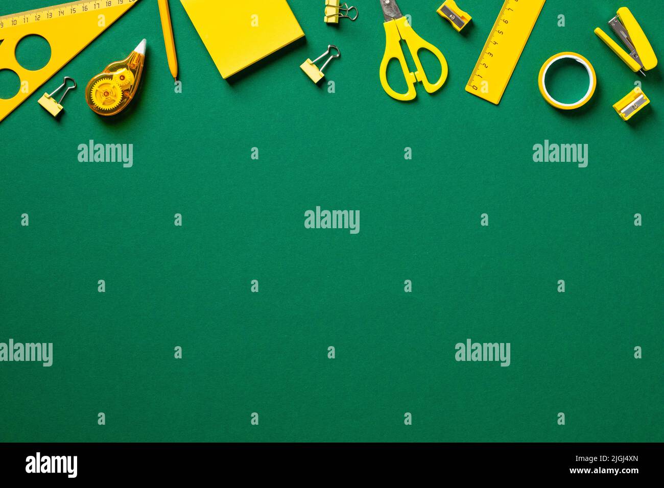 Flat lay yellow school stationery on a green background. Back to school ...