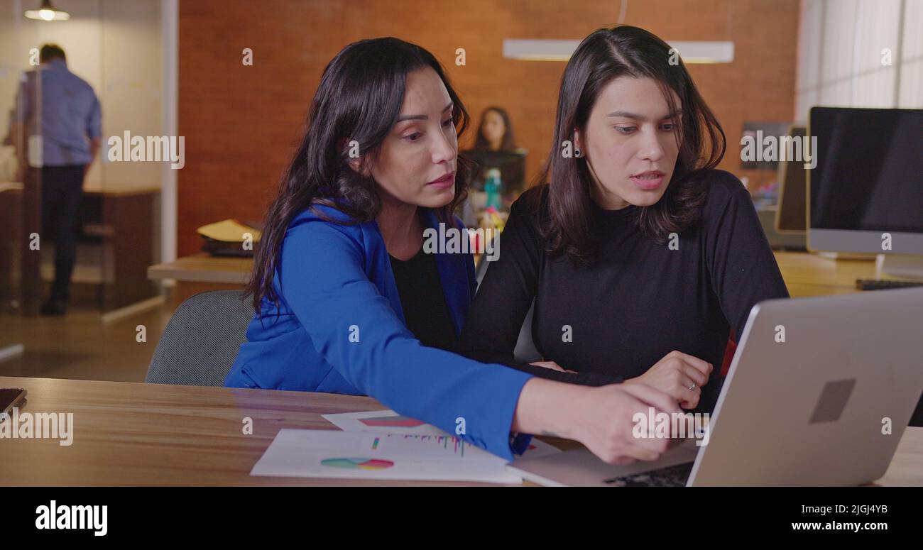 Female business leader pointing at laptop screen with younger staff ...