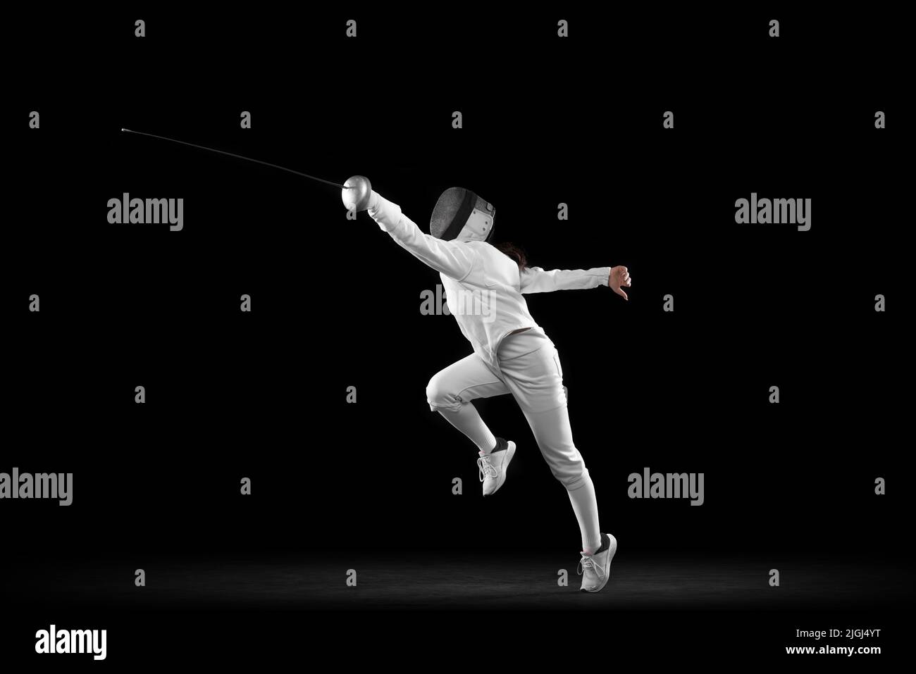 Energetic female fencer in white fencing costume and mask in action ...