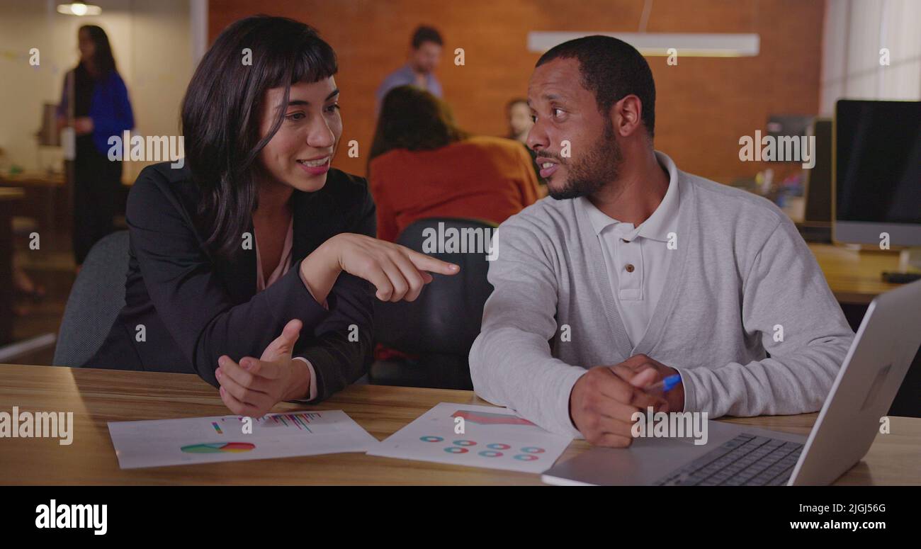 Two diverse employees at work. An African man talking with a hispanic ...