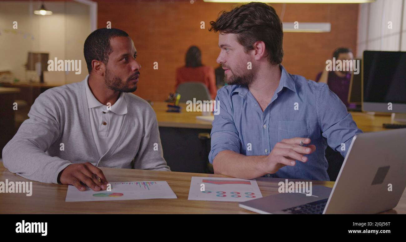 Two diverse millennial employees in front of laptop. A black colleague ...