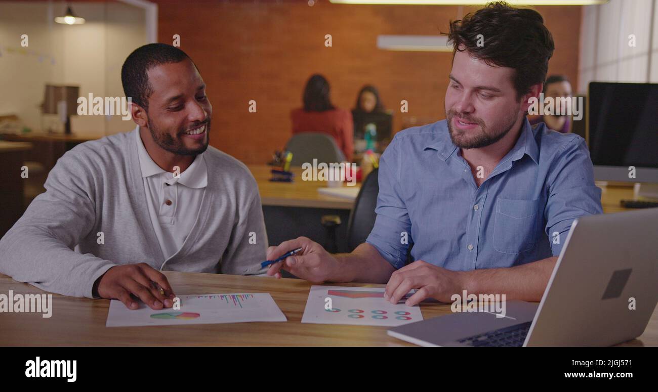 Two diverse millennial employees in front of laptop. A black colleague ...