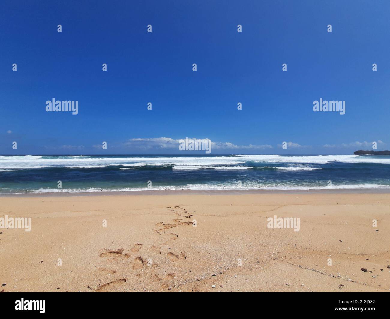 View from a sand beach with foot prints to the sea with waves and blue sky at Sogo beach on East ...