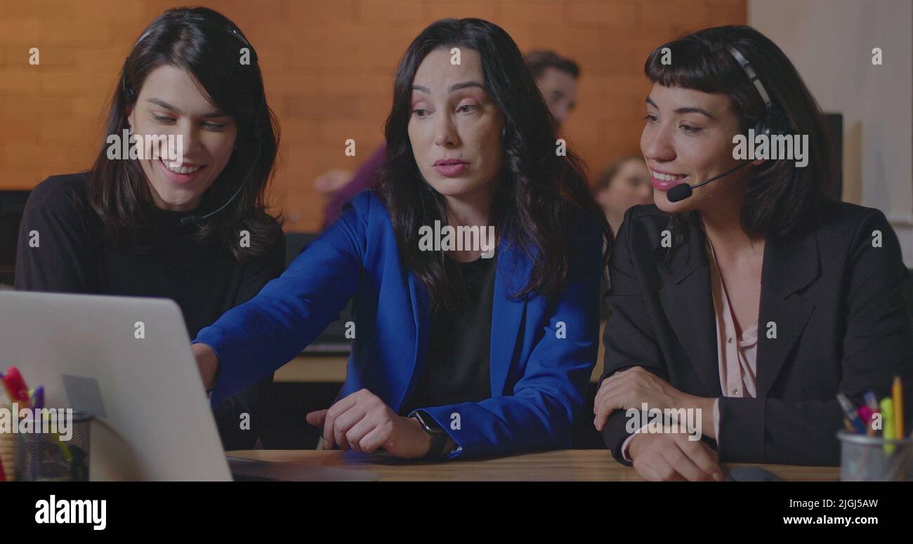 Female executive presenting data to staff in front of computer laptop ...