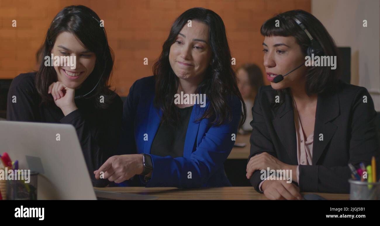 Female executive presenting data to staff in front of computer laptop ...