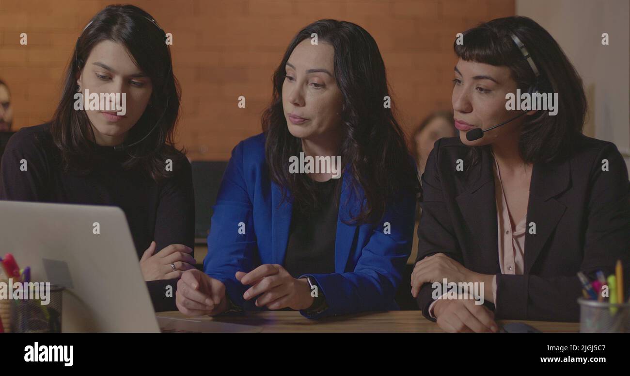 Female executive presenting data to staff in front of computer laptop ...