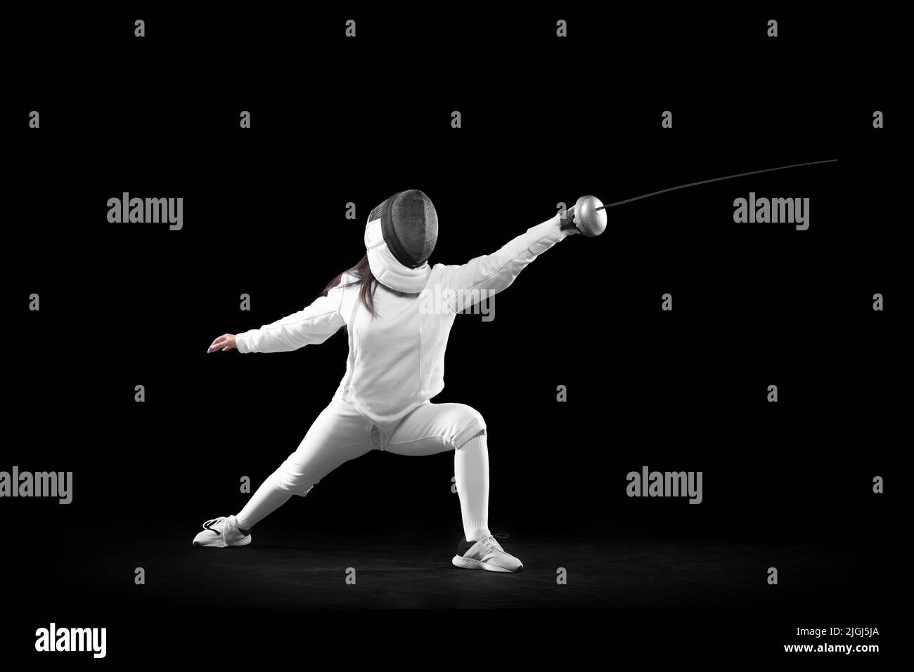 Energetic female fencer in white fencing costume and mask in action ...