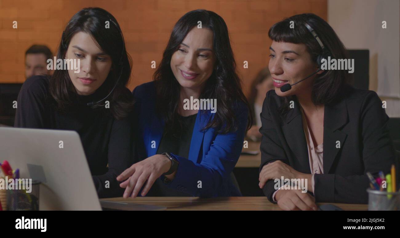 A senior business woman showing computer screen to younger employees ...