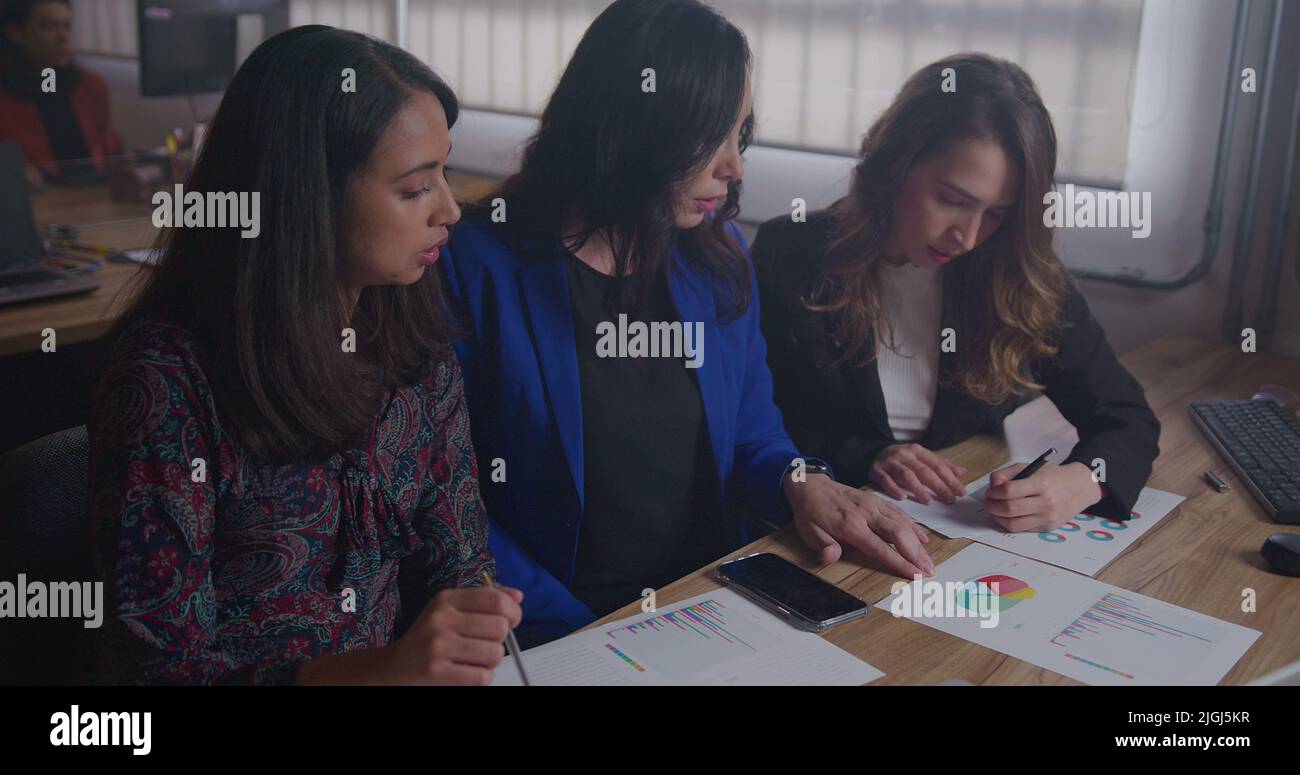 A senior business woman explaining results to female staff showing ...