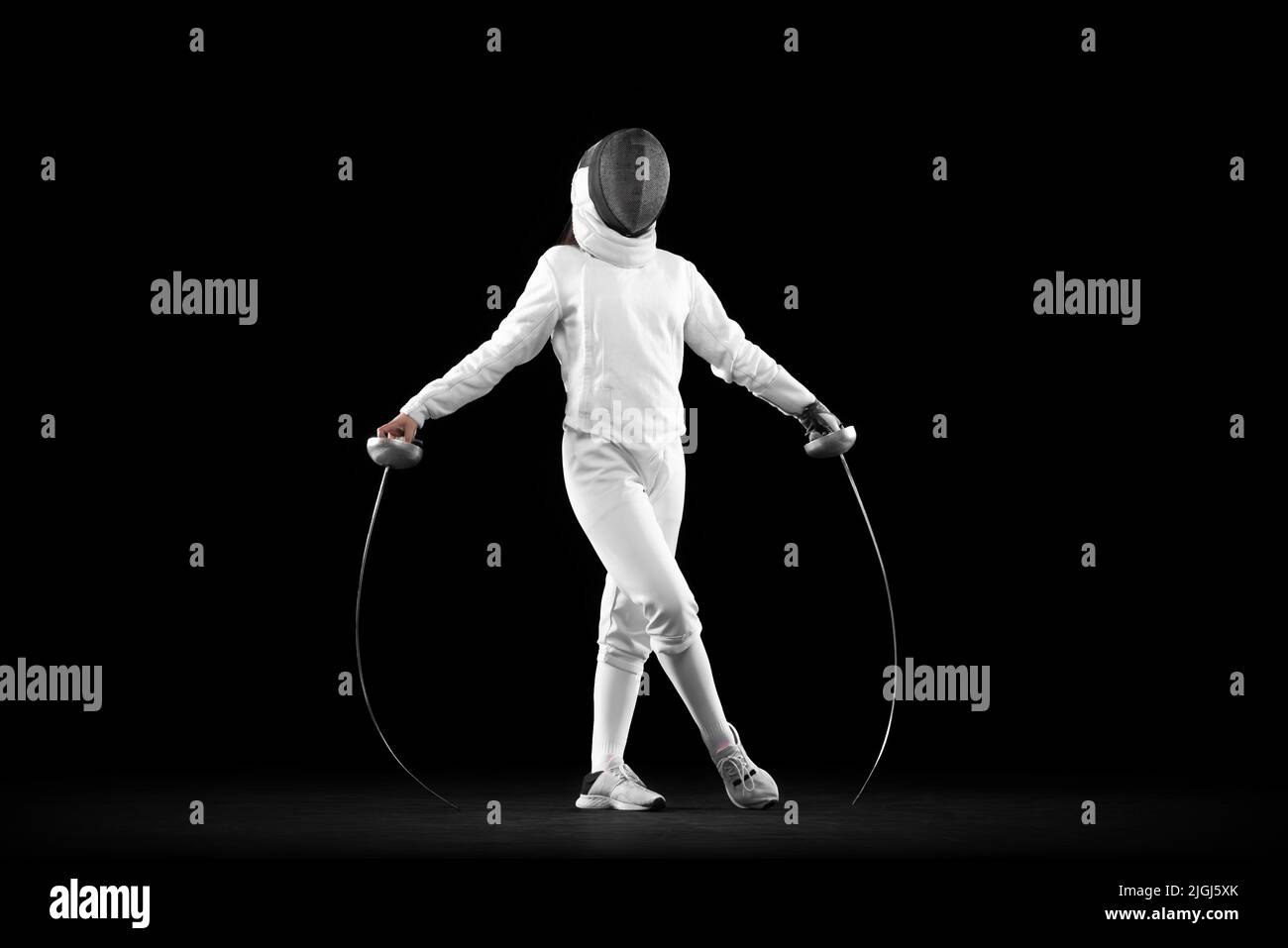 Young serious girl, beginner fencer in white fencing costume standing ...