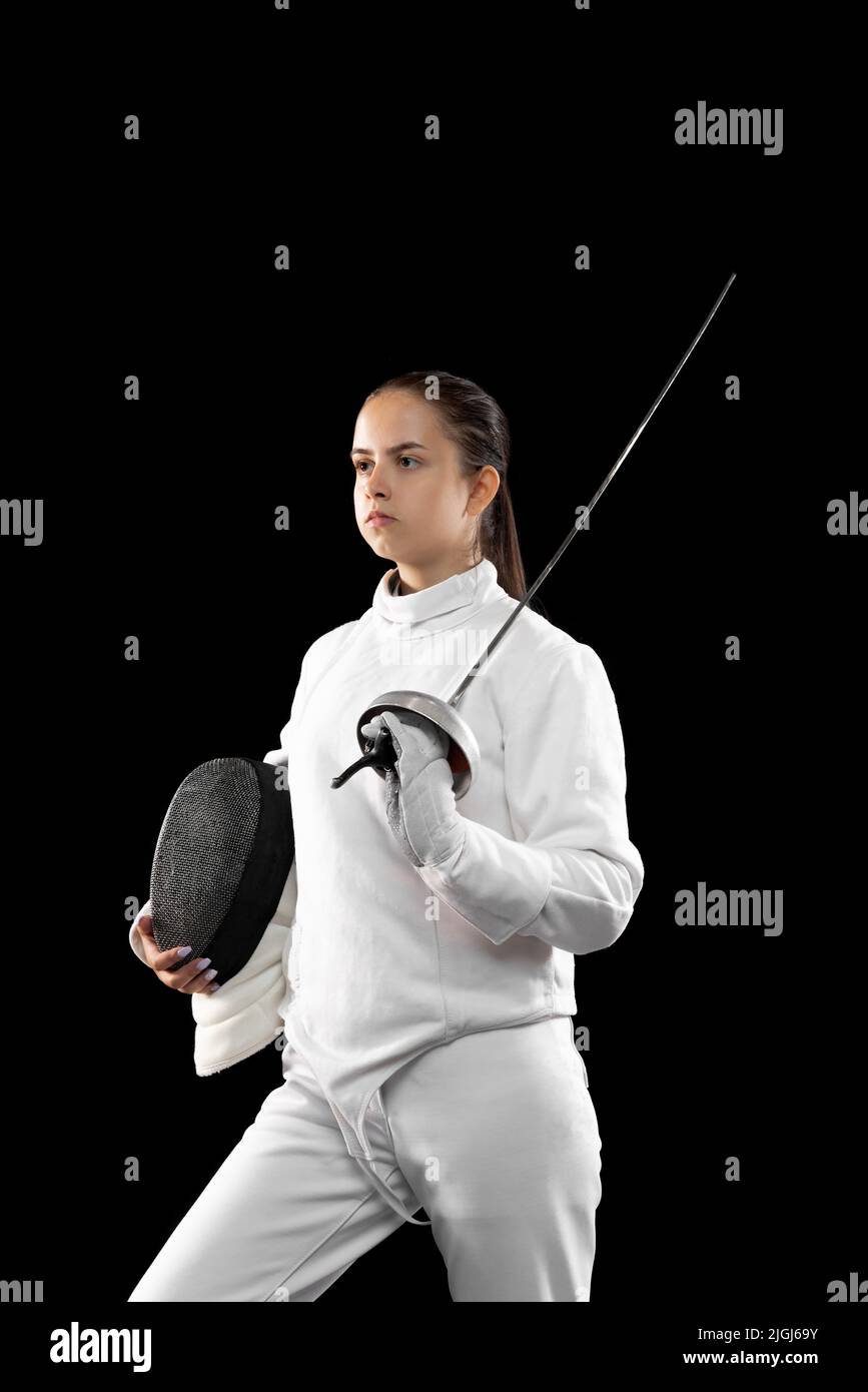 Young serious girl, beginner fencer in white fencing costume standing ...