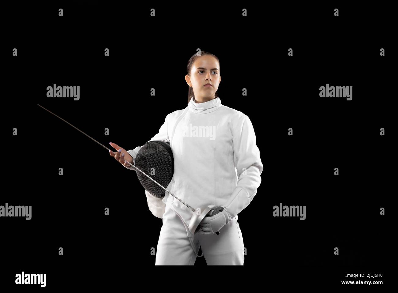 Young serious girl, beginner fencer in white fencing costume standing ...