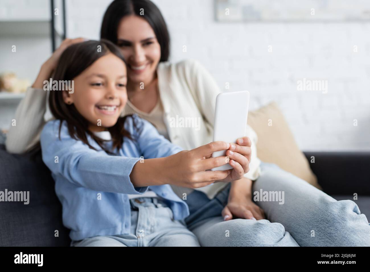 happy girl taking selfie on mobile phone with nanny on blurred ...