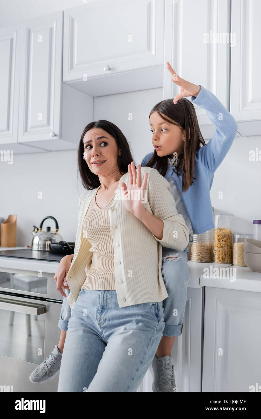 girl sitting on worktop in kitchen and scaring nanny Stock Photo - Alamy
