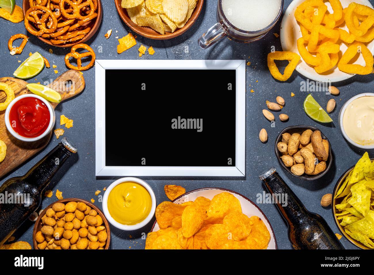 Beer with various salted snacks set. Black table background with ...