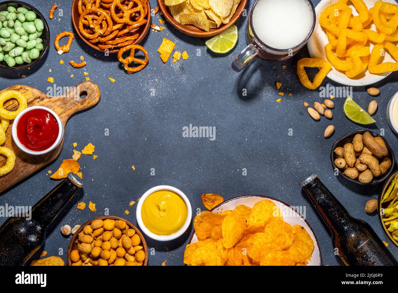 Beer with various salted snacks set. Black table background with ...