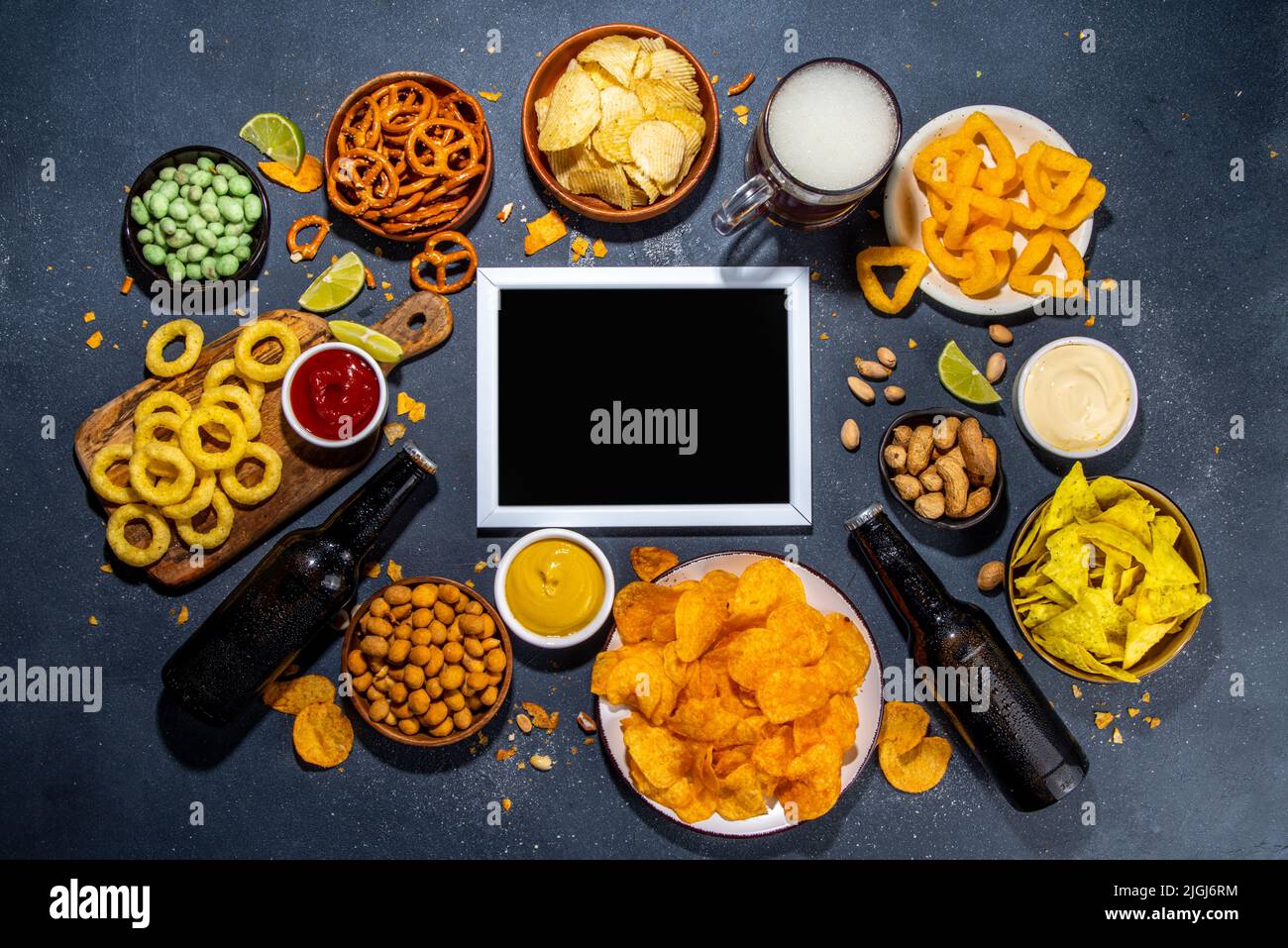 Beer with various salted snacks set. Black table background with ...