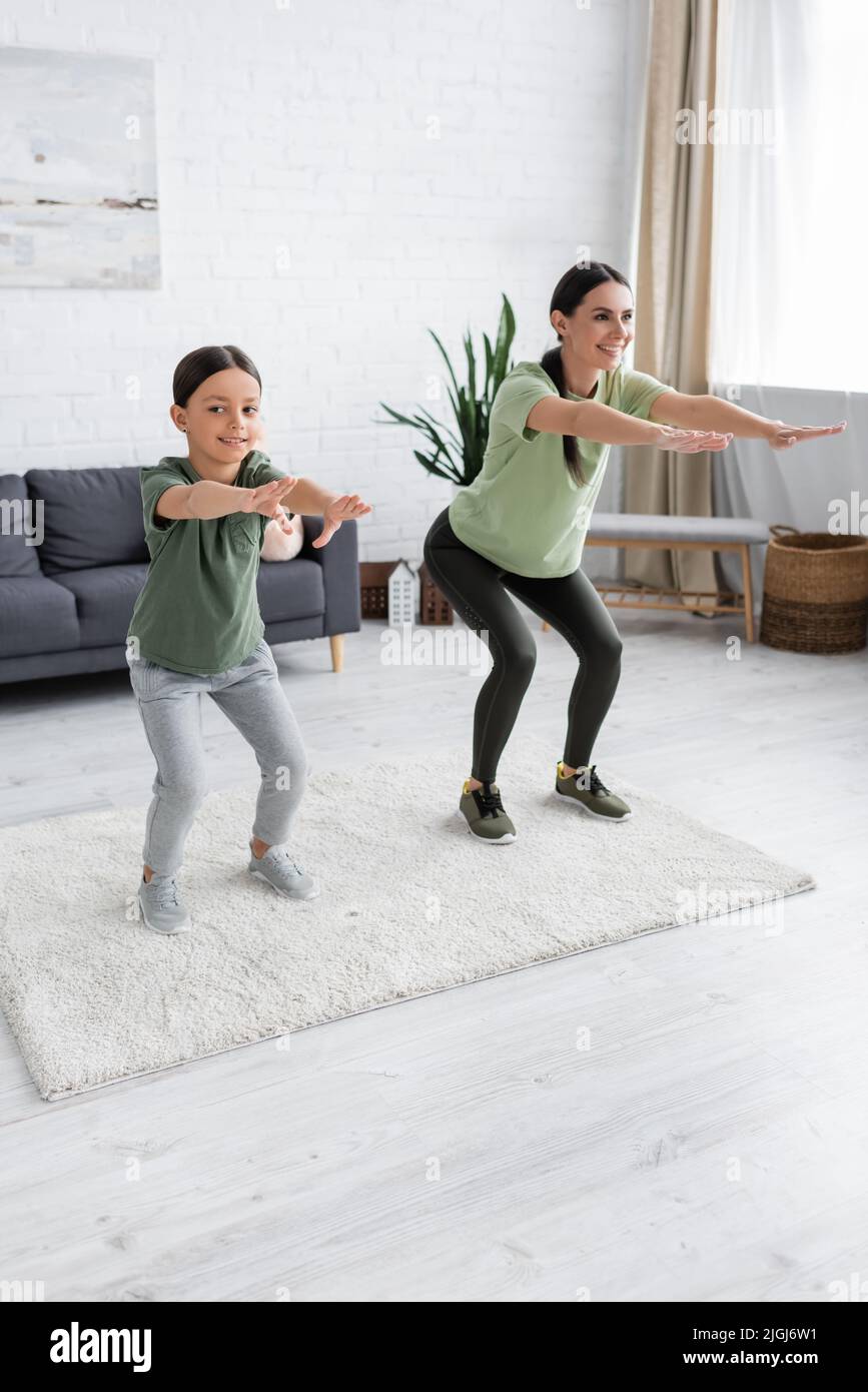full length of positive nanny and child doing sit ups with outstretched ...