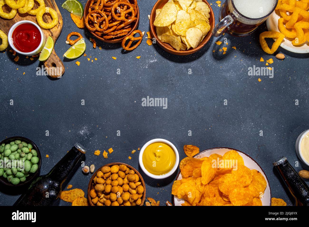 Beer with various salted snacks set. Black table background with ...