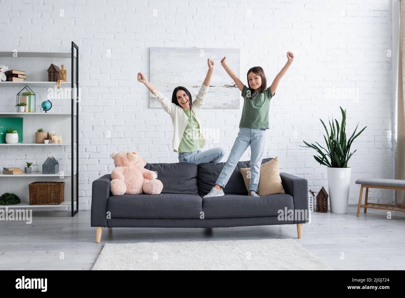 excited babysitter and girl with outstretched hands in modern living ...