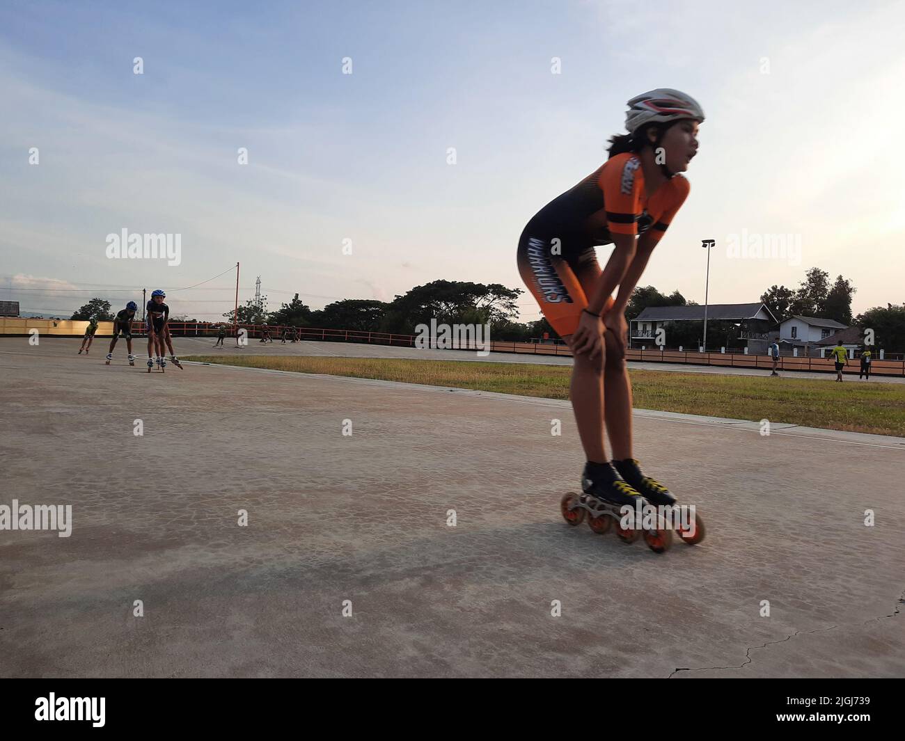 Young mixed Inline scater while training on a track outdoors at stadion ...