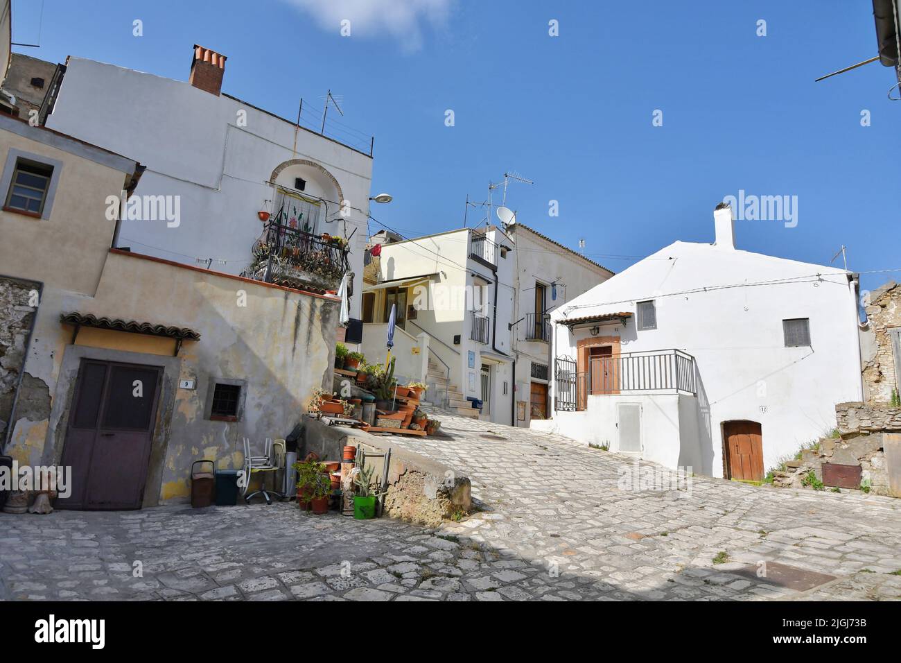 A narrow street between the old houses of Grottole, a village in the ...