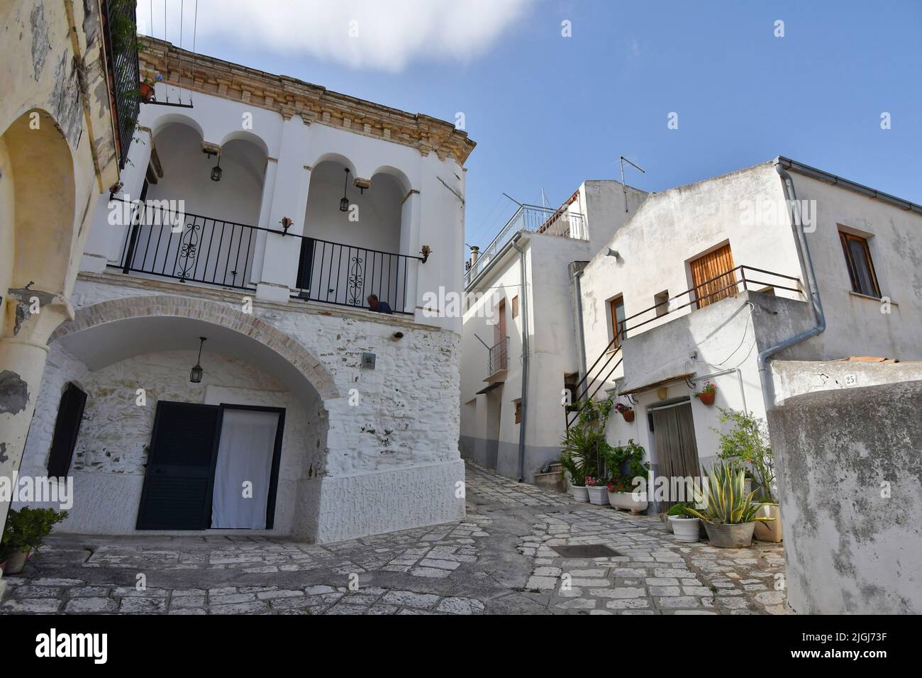 A narrow street between the old houses of Grottole, a village in the ...