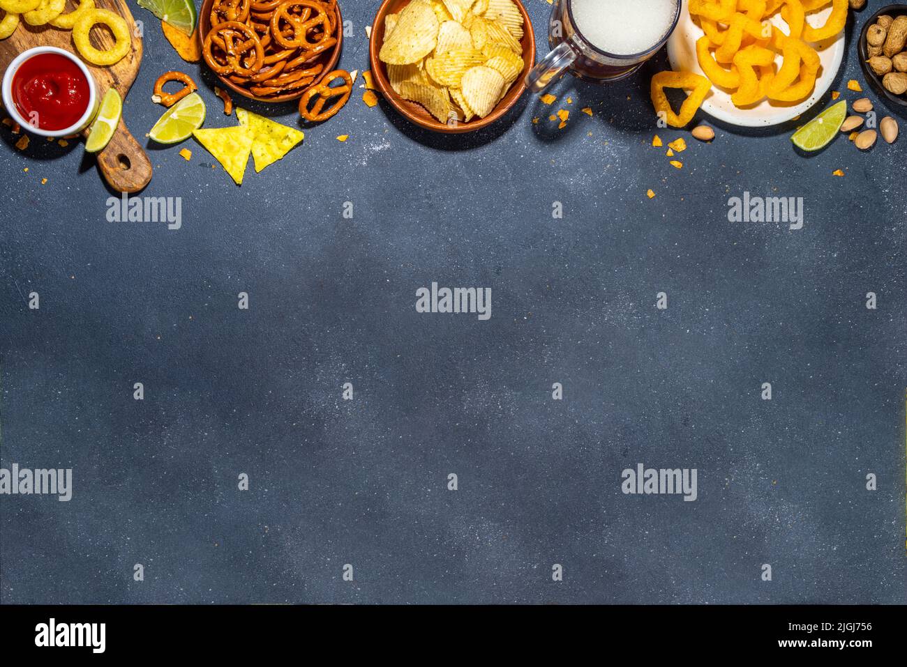Beer with various salted snacks set. Black table background with ...