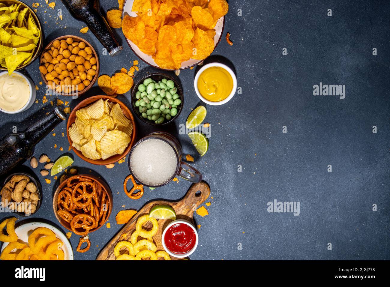 Beer with various salted snacks set. Black table background with ...