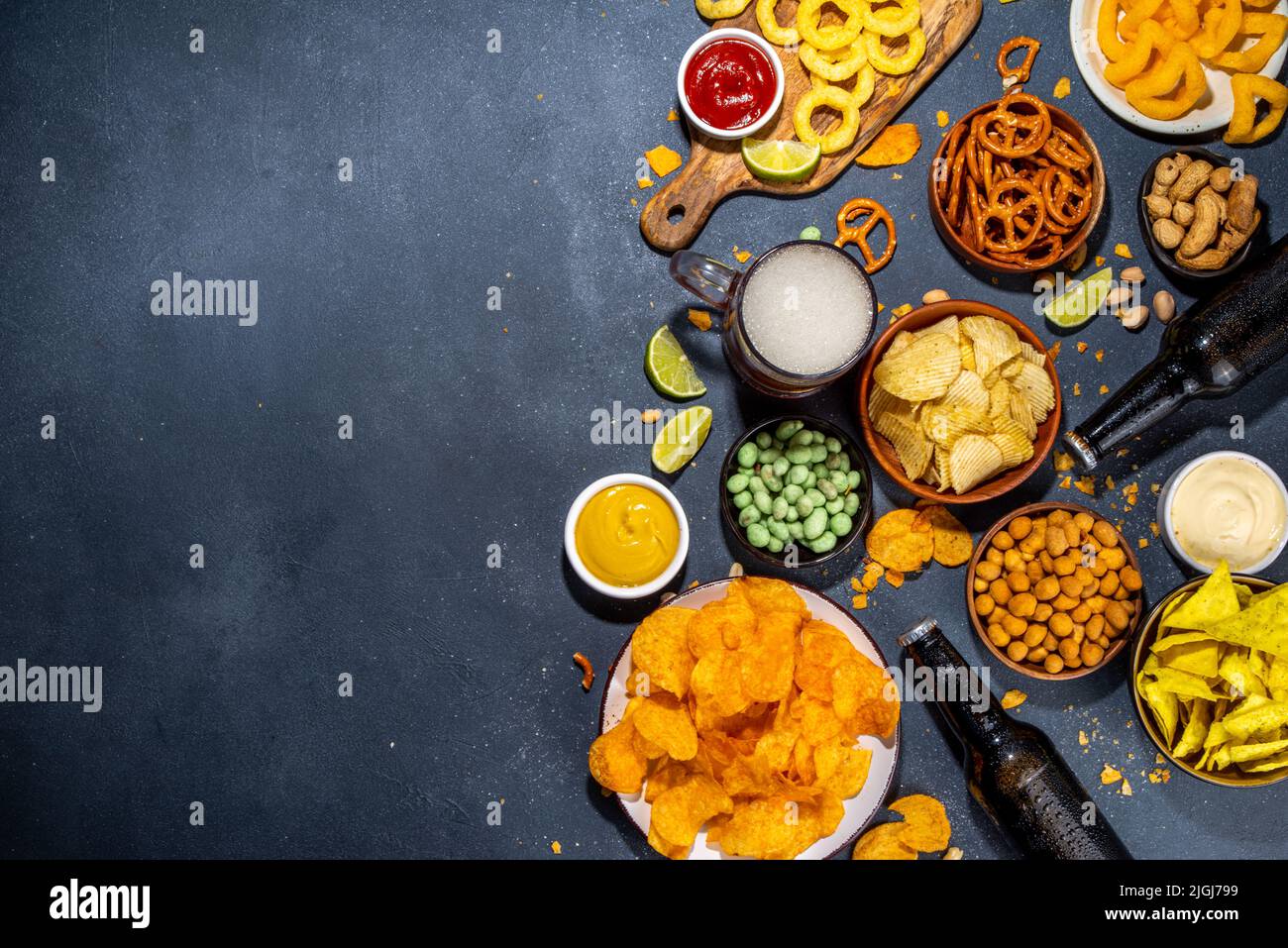 Beer with various salted snacks set. Black table background with ...