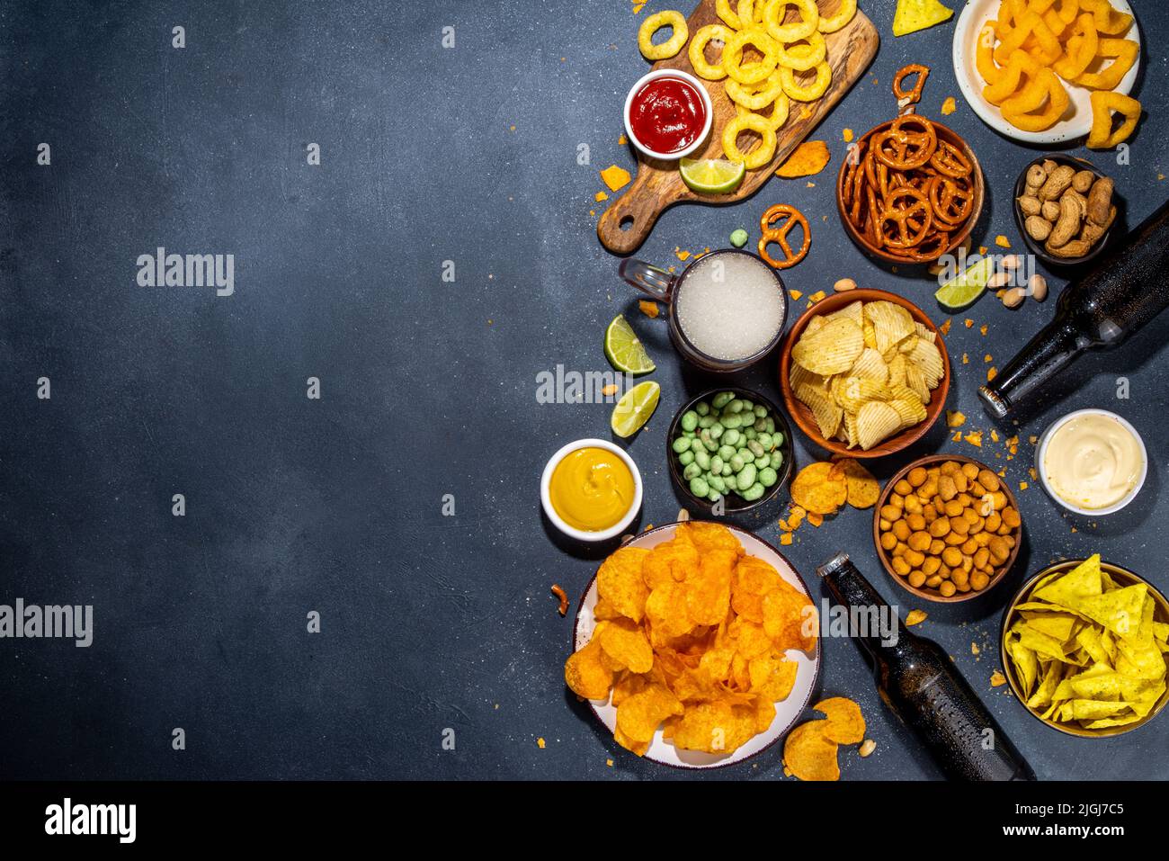 Beer with various salted snacks set. Black table background with ...