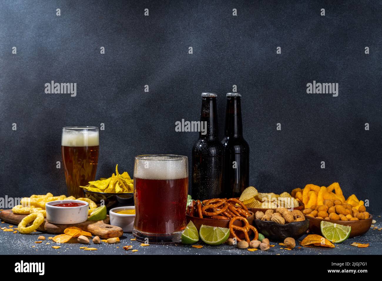 Beer with various salted snacks set. Black table background with ...