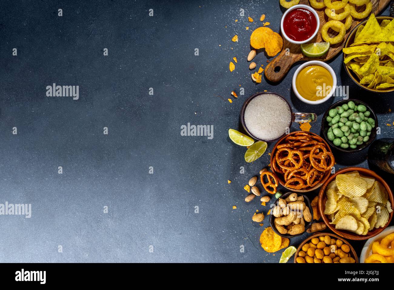 Beer with various salted snacks set. Black table background with ...
