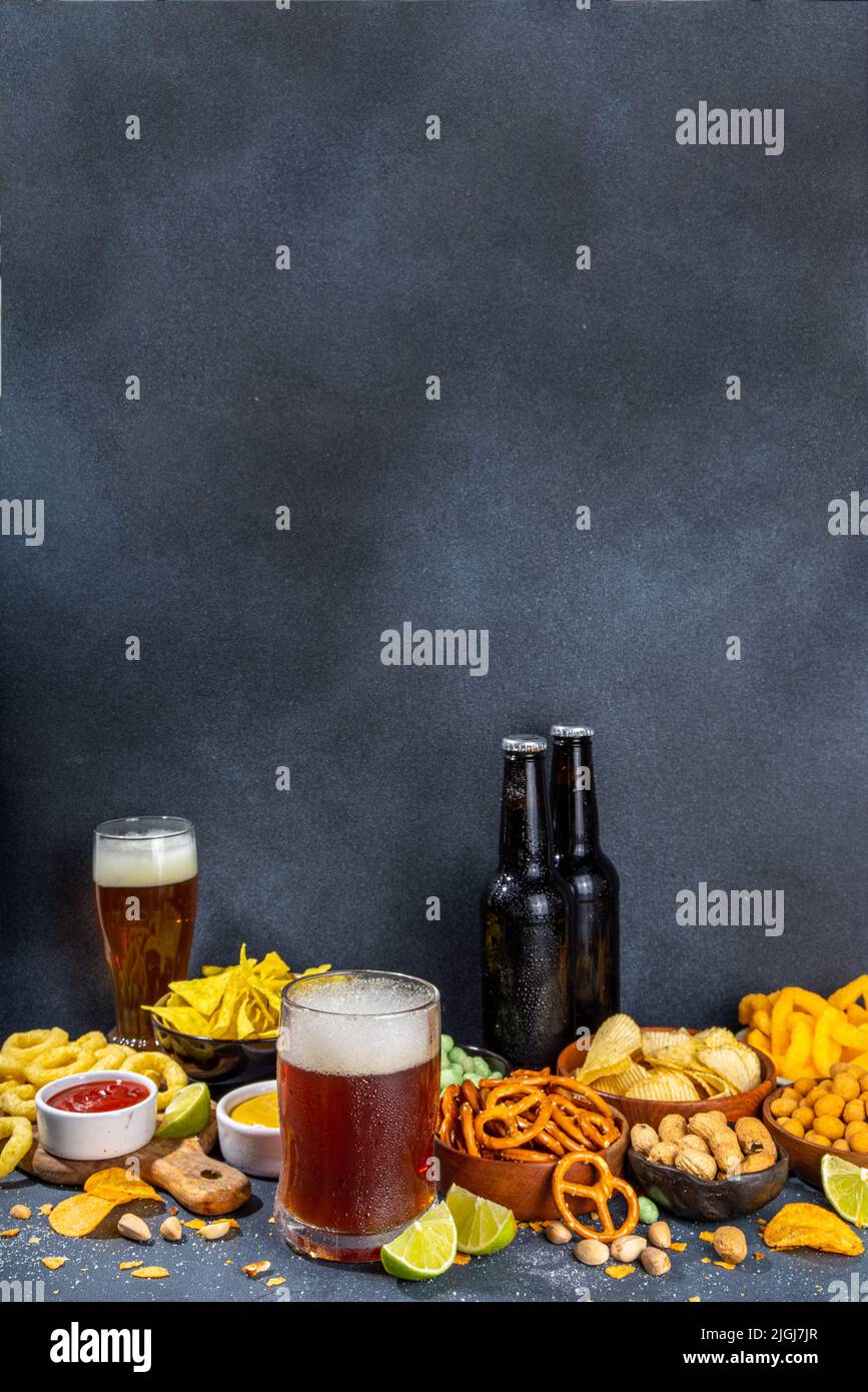 Beer with various salted snacks set. Black table background with ...