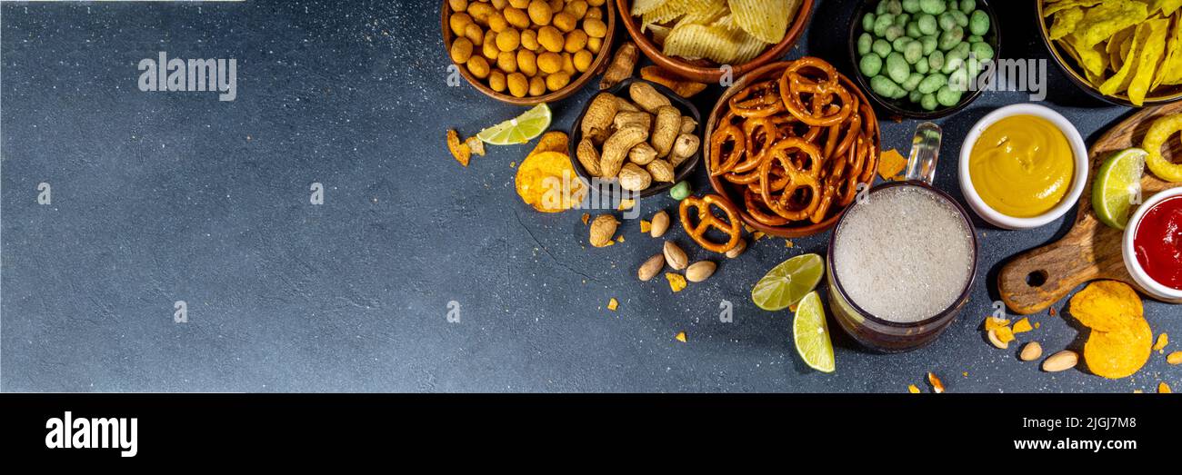 Beer with various salted snacks set. Black table background with ...