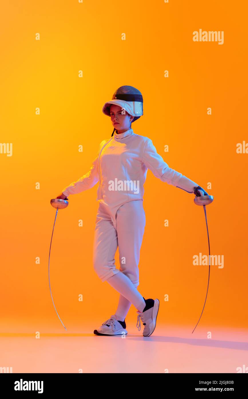 Studio shot of professional fencer in white fencing costume and mask in ...