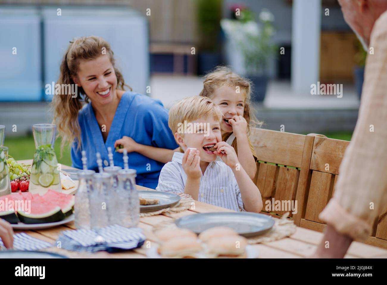 Multi generation family having garden party celebration, grandfather is ...