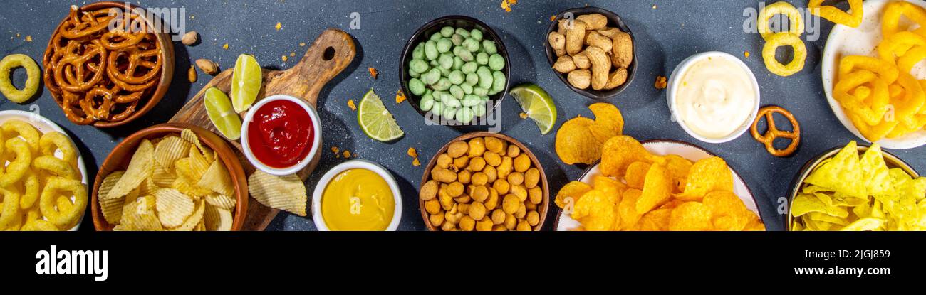Various unhealthy salty bar snacks set. Dark grey table background with ...