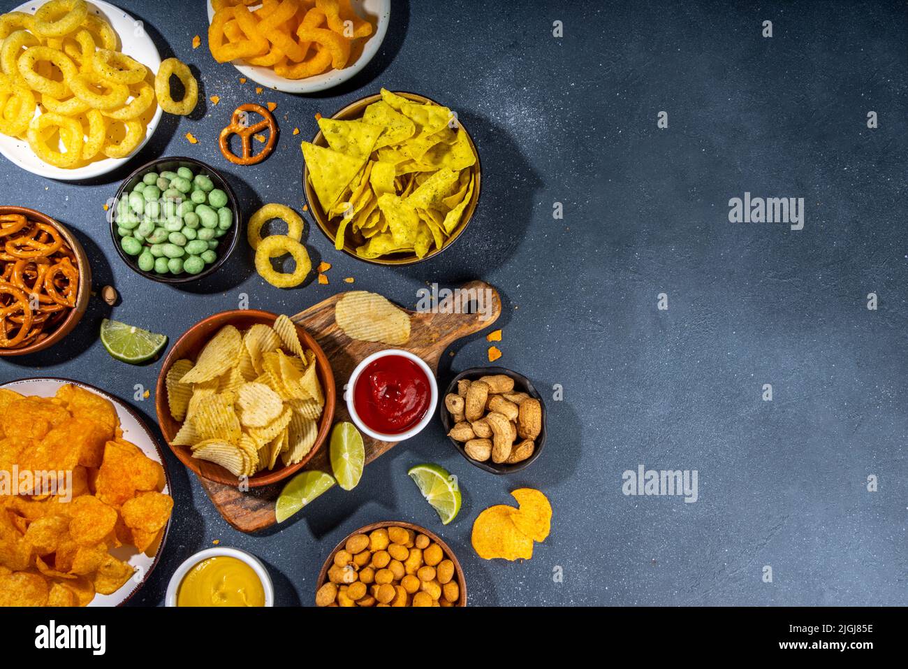 Various unhealthy salty bar snacks set. Dark grey table background with traditional party snacks ...