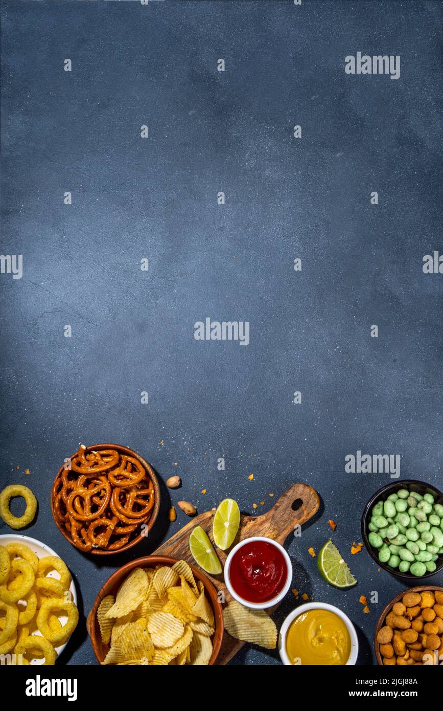 Various unhealthy salty bar snacks set. Dark grey table background with ...
