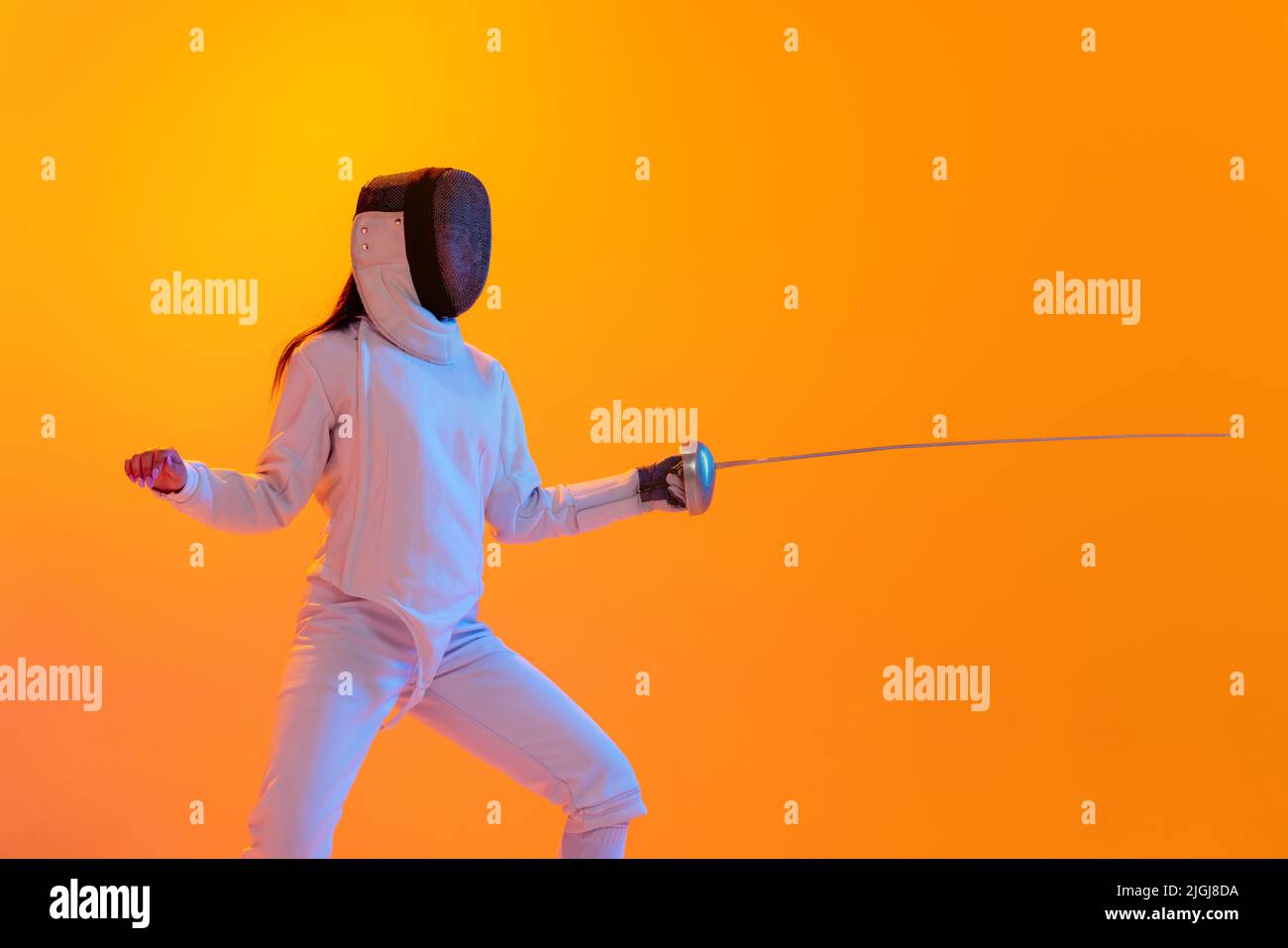 Studio shot of professional fencer in white fencing costume and mask in ...