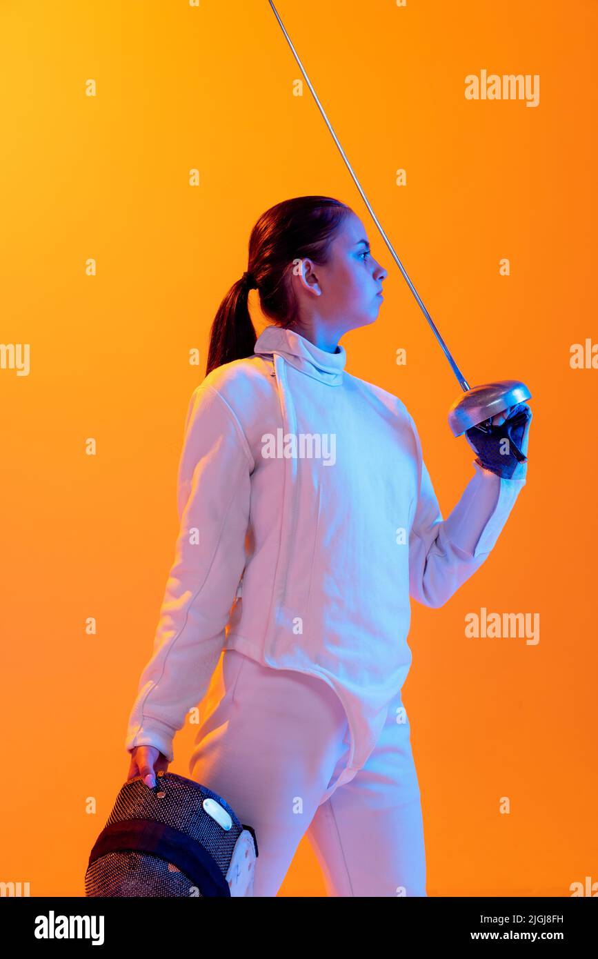 Studio shot of professional fencer in white fencing costume and mask in ...