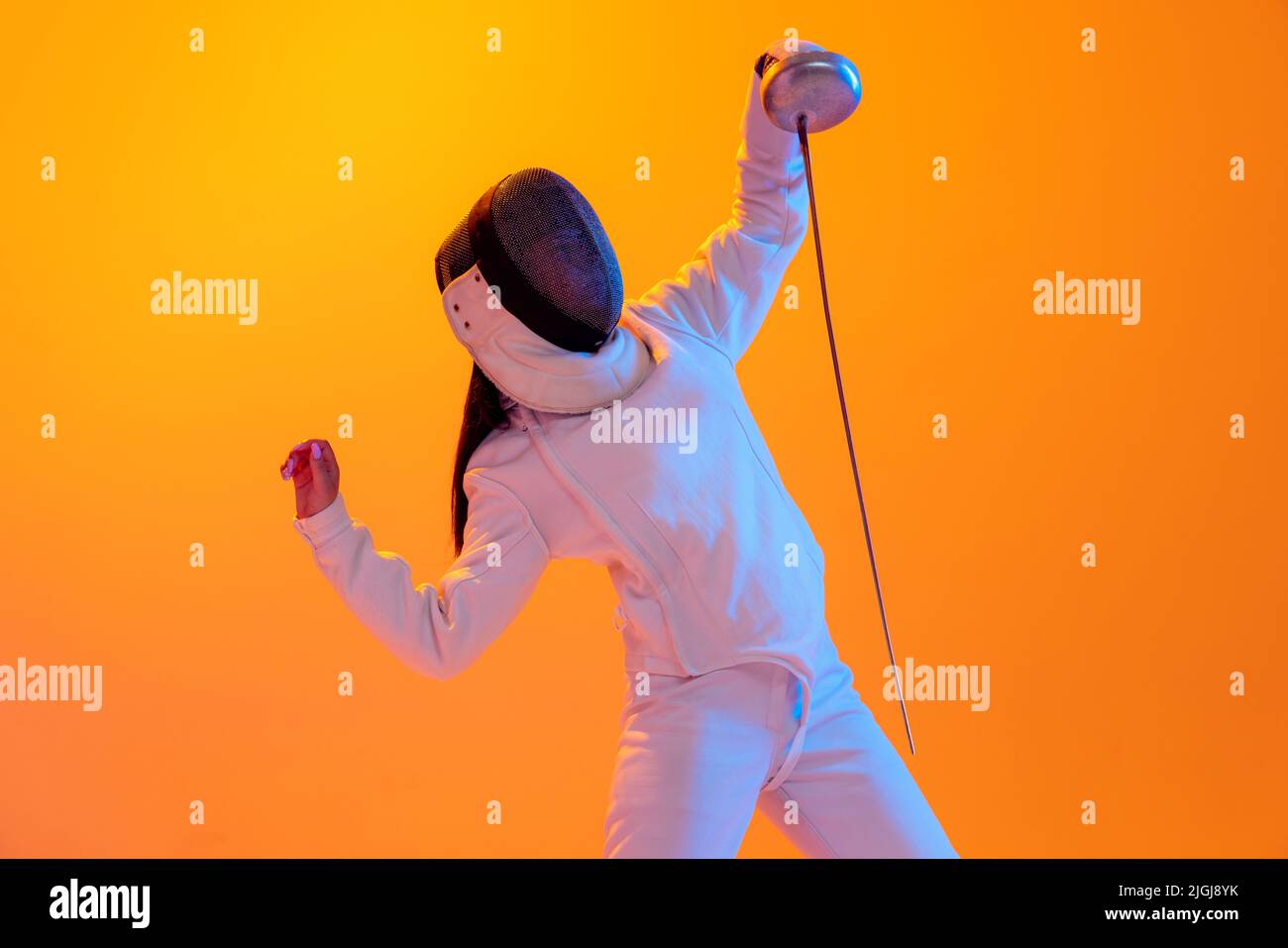 Studio shot of professional fencer in white fencing costume and mask in ...