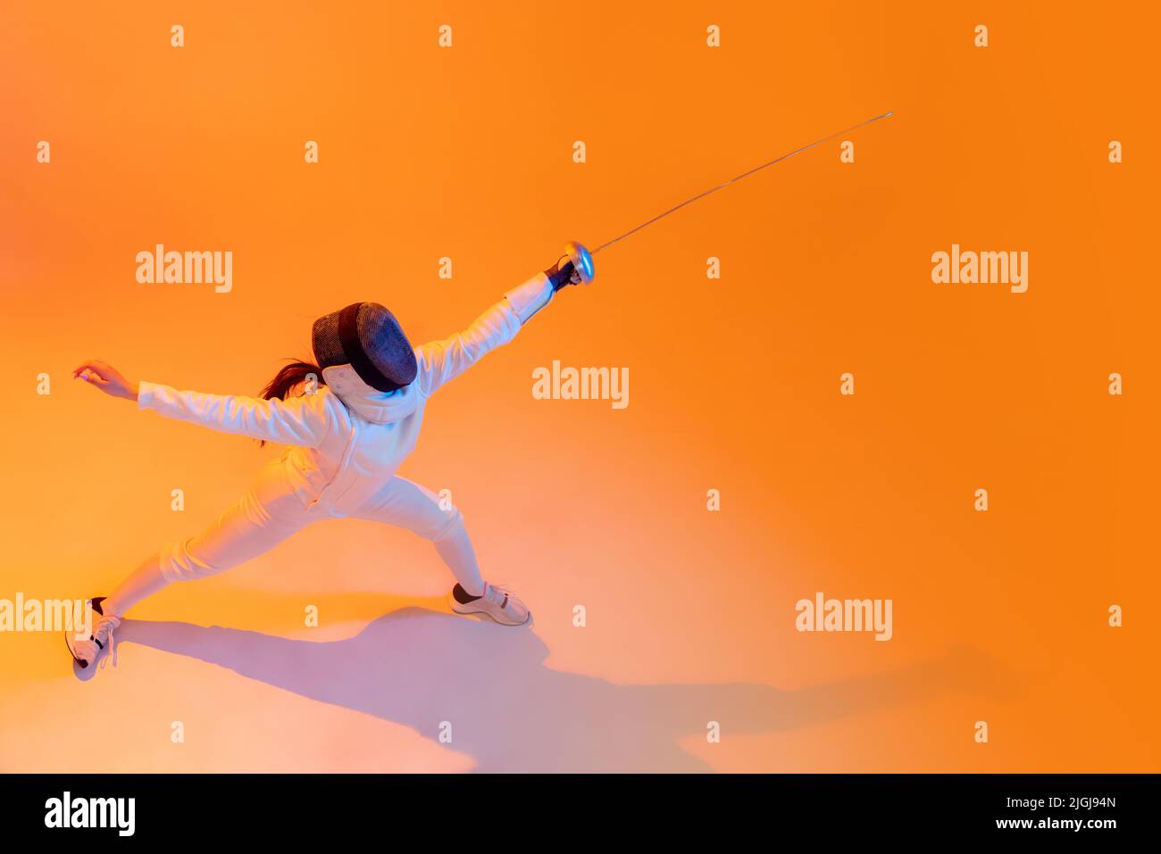 Aerial view of professional fencer in white fencing costume and mask in ...