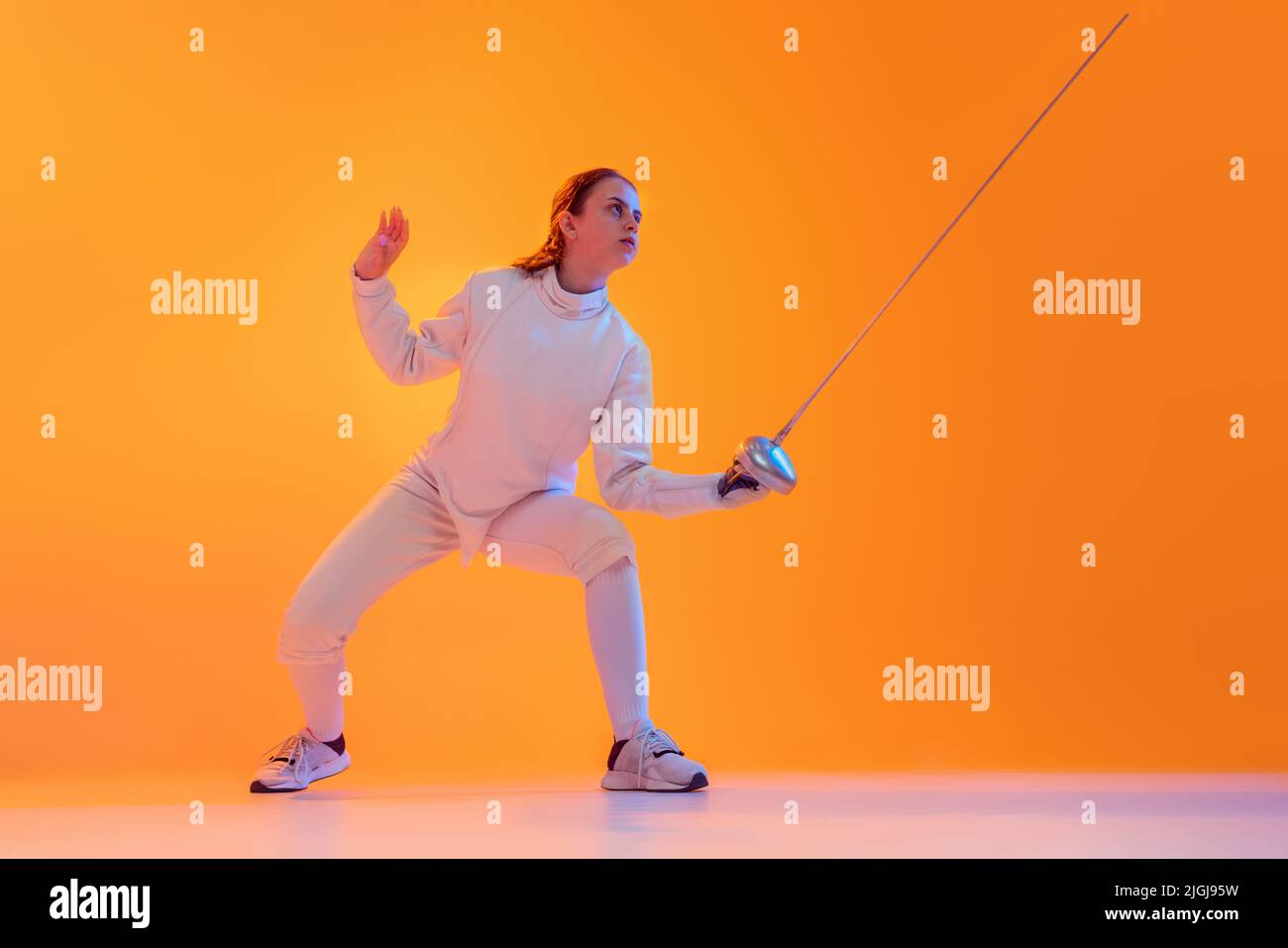 Studio shot of professional fencer in white fencing costume and mask in ...
